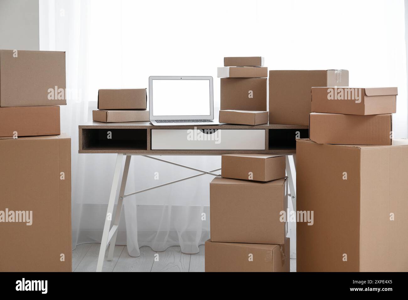Blank laptop on table with moving boxes near window in room Stock Photo ...