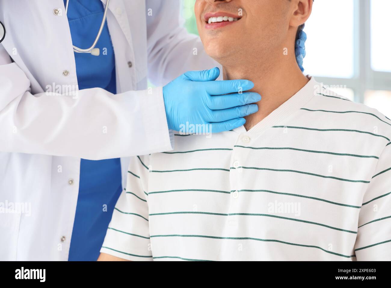 Female endocrinologist examining thyroid gland of man in clinic ...