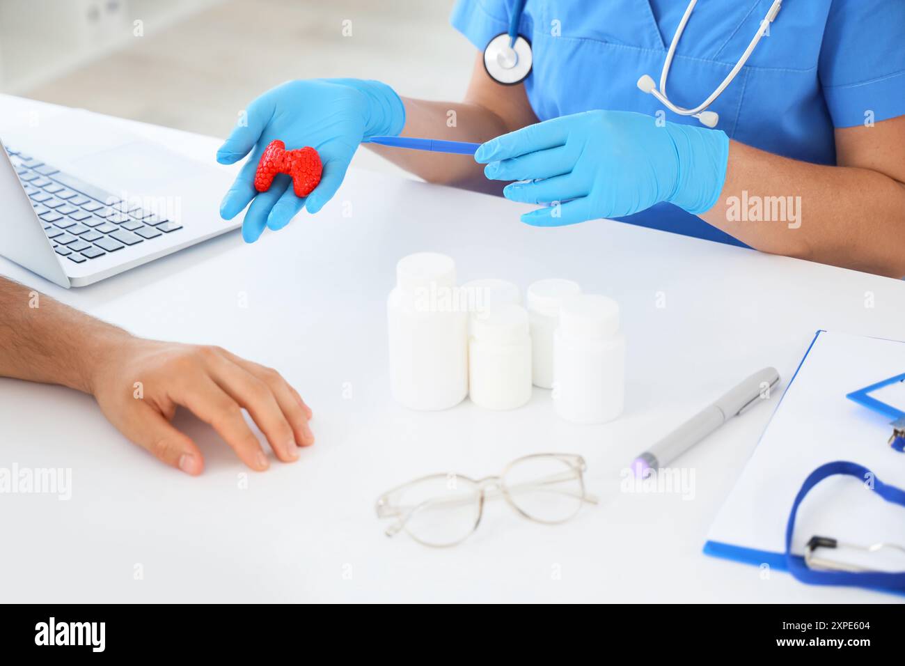 Female endocrinologist showing thyroid gland model to man in clinic ...
