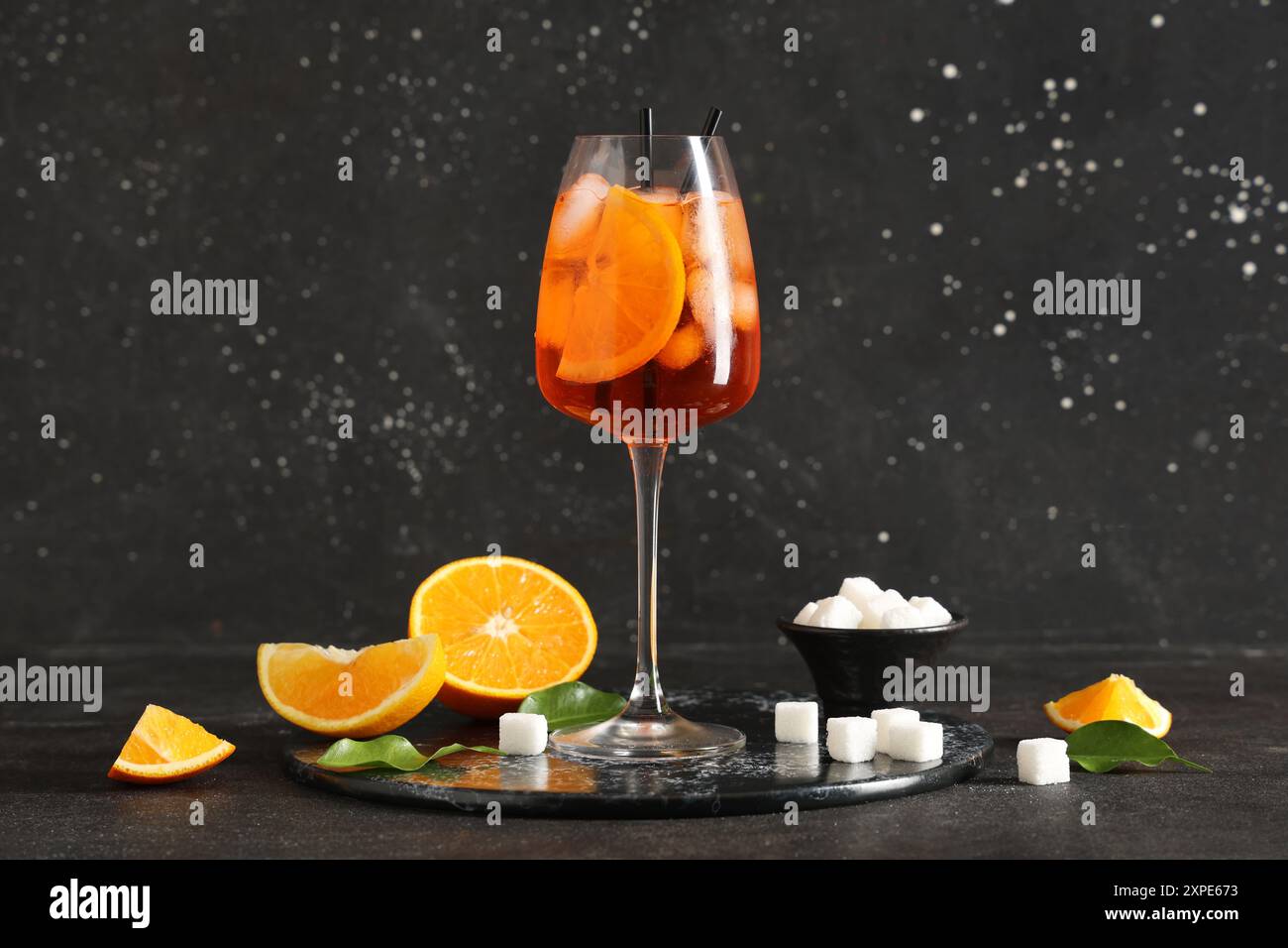 Glass of Aperol spritz cocktail and bowl with sugar on black background ...