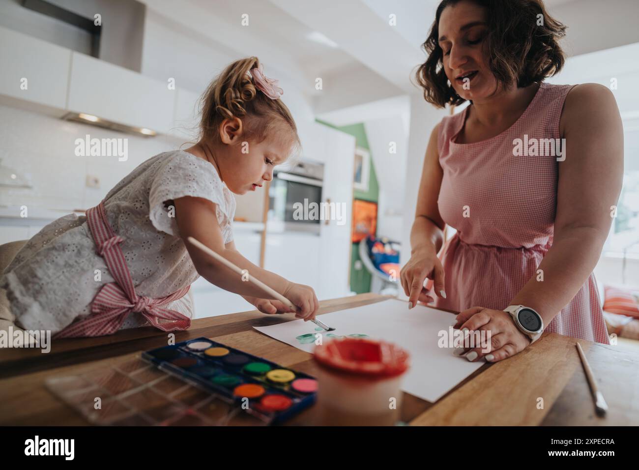 Mother and daughter painting together indoors, bonding and enjoying ...