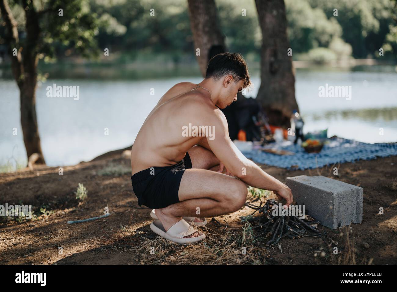Young man preparing a barbeque fire during a scenic mountain picnic by ...