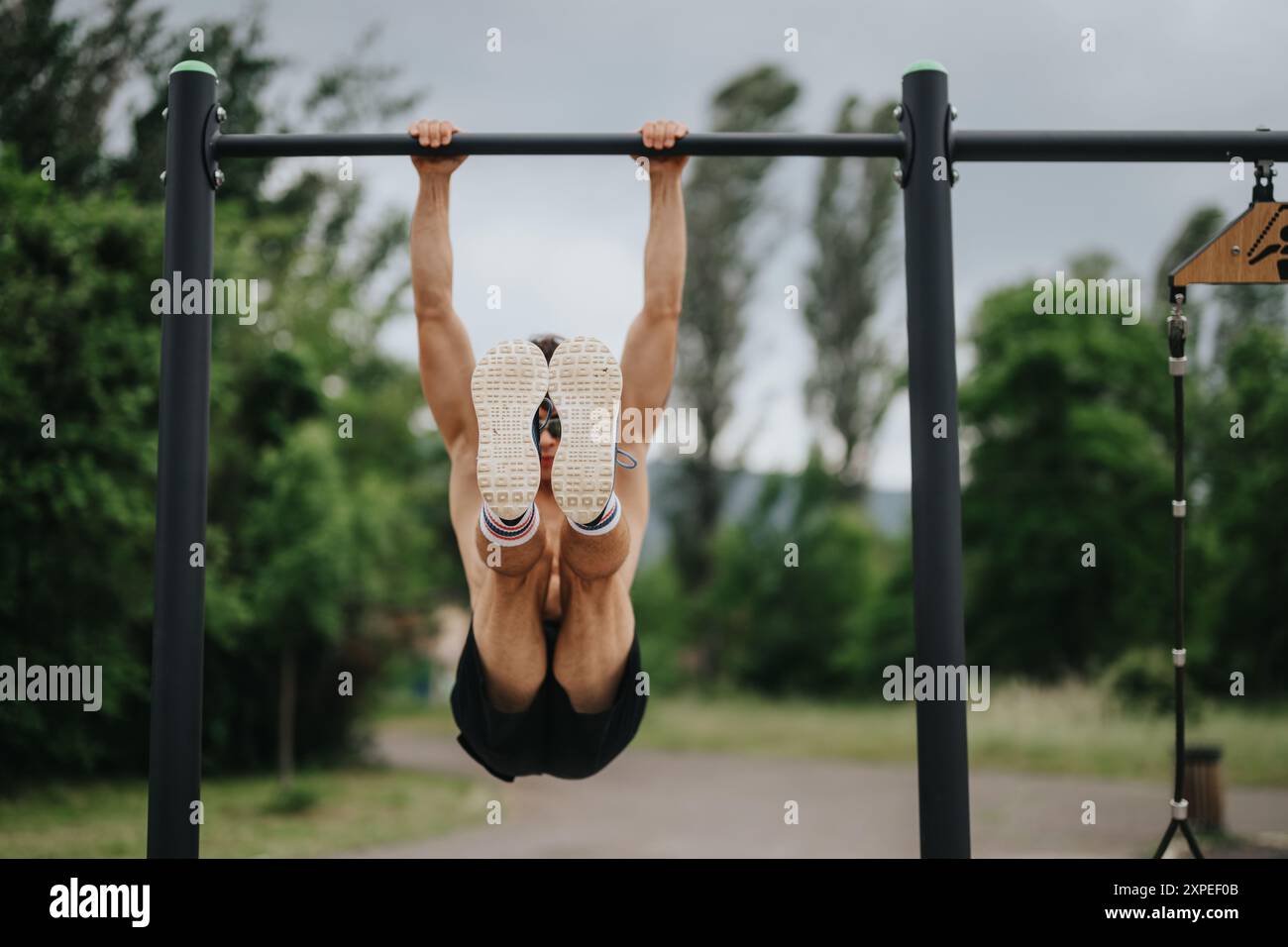 Man performing outdoor calisthenics workout on horizontal bar in park ...