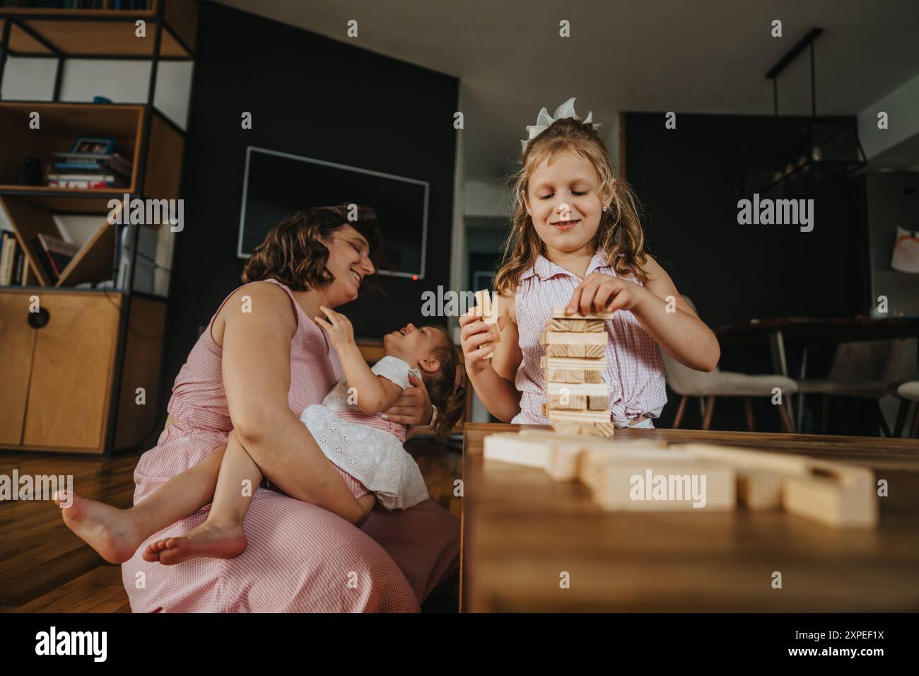 Mother playing with daughters at home, building blocks and sharing quality family time Stock ...