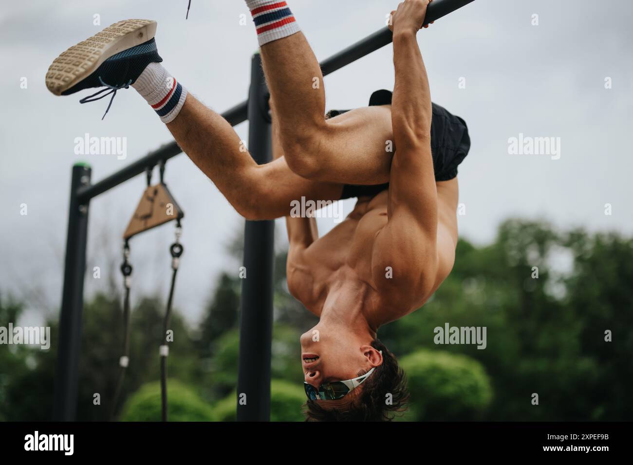 Man performing an outdoor calisthenics workout on bars with impressive ...