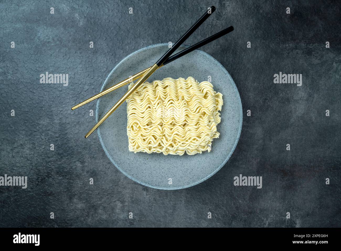 A plate of instant noodles with chopsticks on top. The plate is on a ...