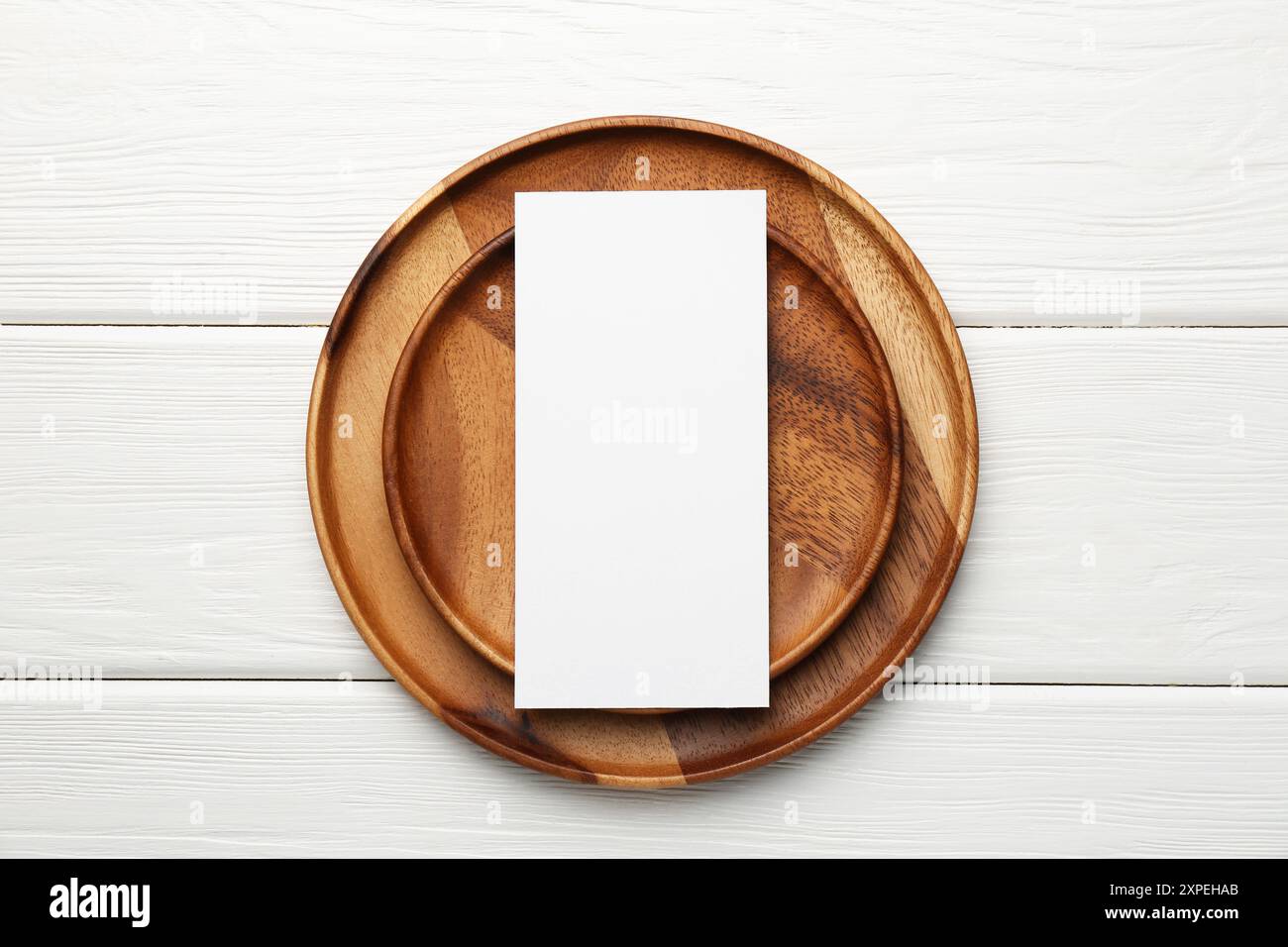 Empty menu and plates on white wooden table, top view. Mockup for ...