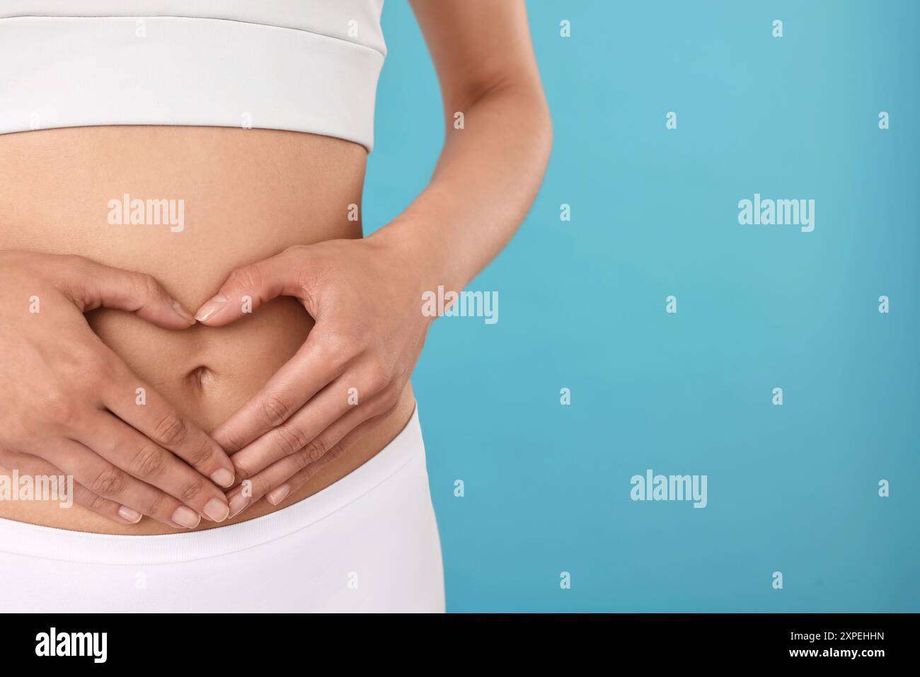 Healthy digestion. Woman making heart shape with hands near her belly ...