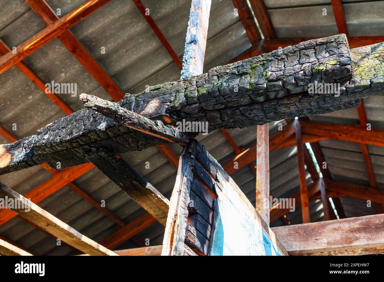 Charred log is hanging from the ceiling of a building. Charred wood has ...