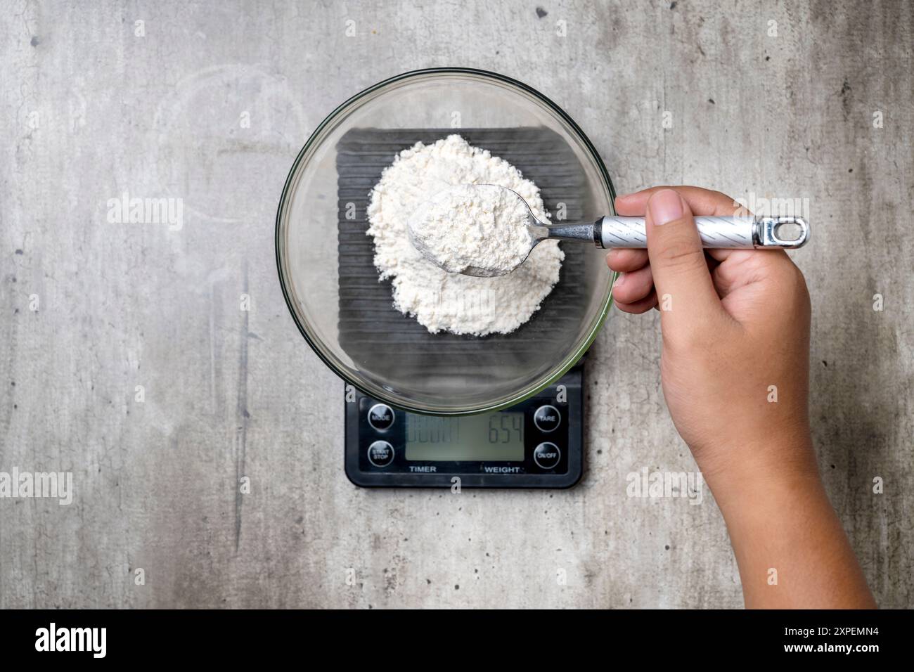A person is measuring flour on a scale. The scale reads 664 grams Stock ...