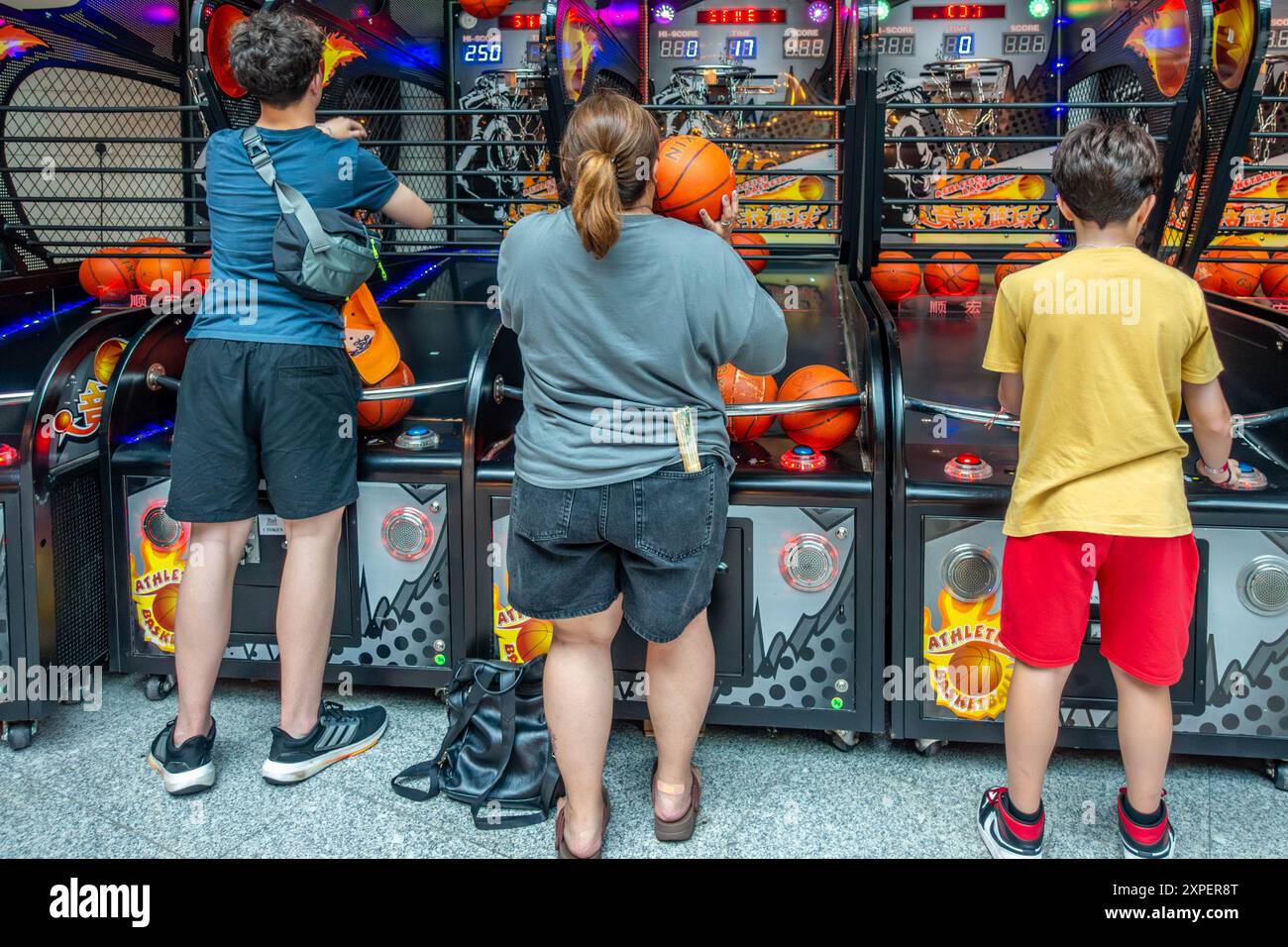 A family all playing a coin-operated basketball game where the aim is ...