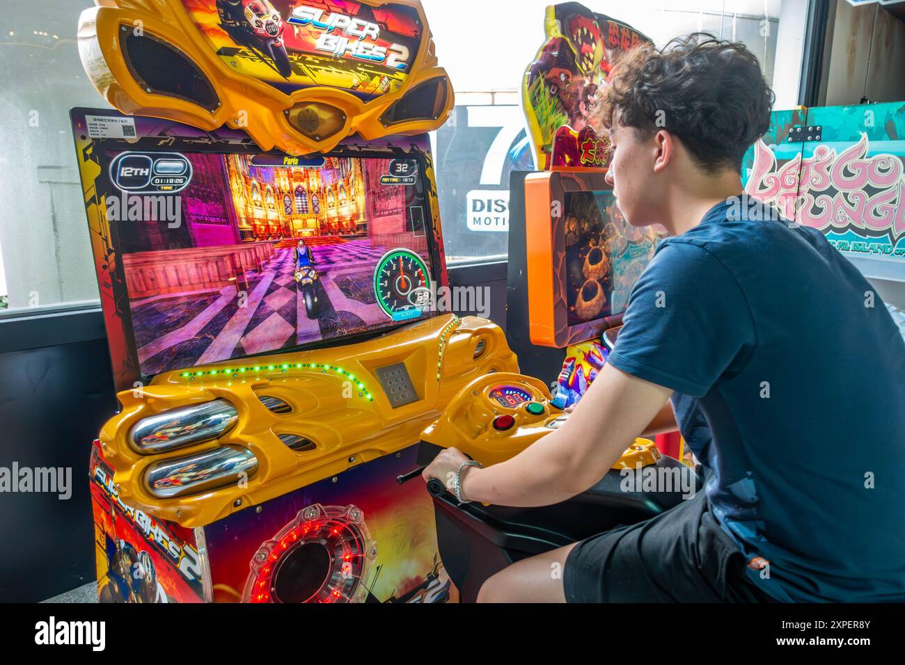 A boy playing a motorcycle racing video game at the amusements arcade ...