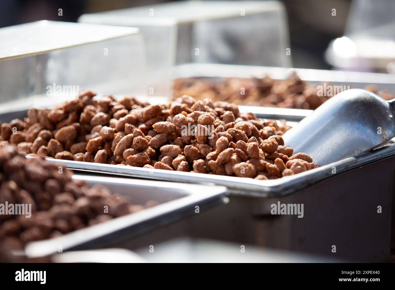 A view of several trays of roasted assorted nuts, on display at a food ...
