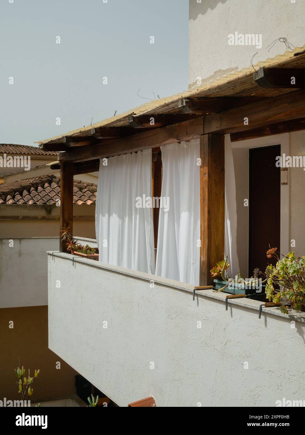 Vertical view of a cozy balcony corridor with white curtains and doors ...