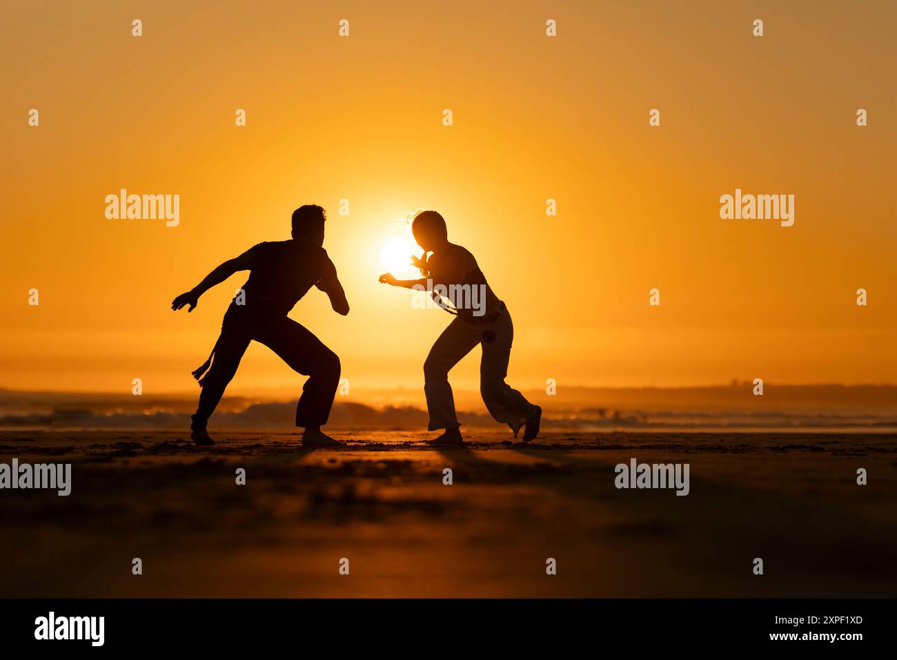 Two people are playing a game of karate on the beach Stock Photo - Alamy