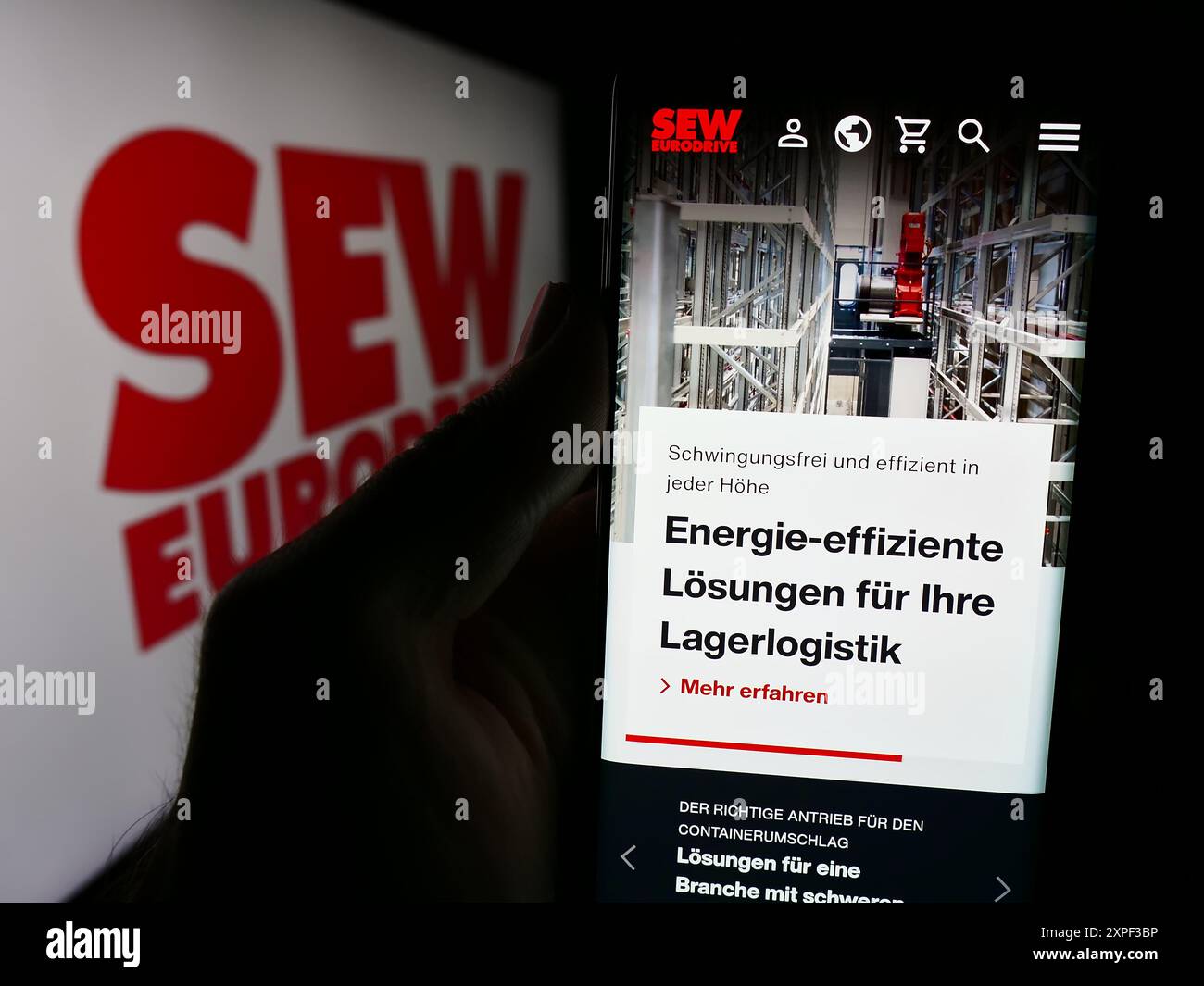 Person holding cellphone with webpage of German engineering company SEW ...