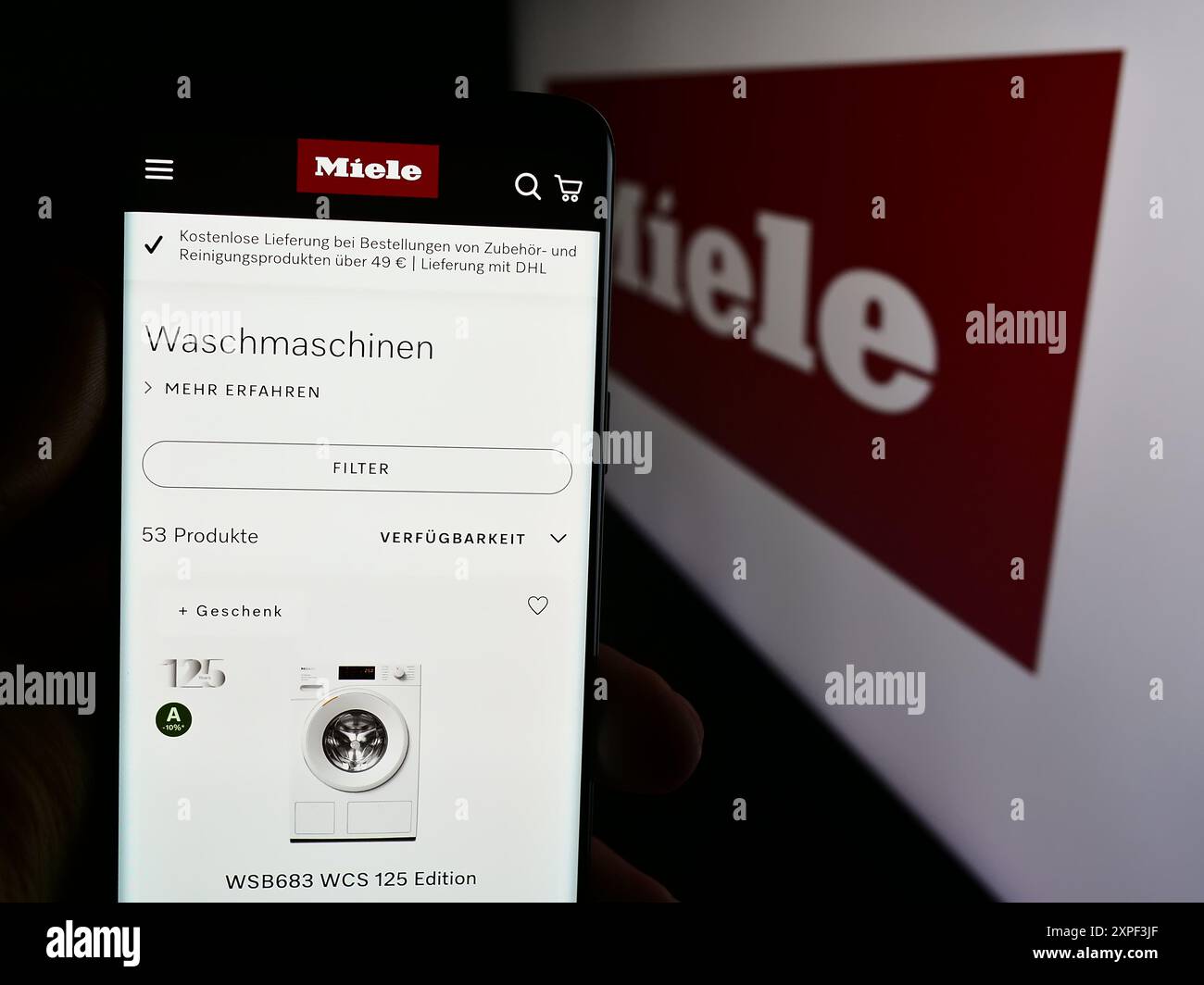 Person holding mobile phone with web page of German household ...