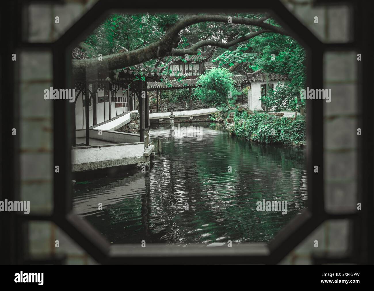 A view through a window frame of a Suzhou Chinese garden. The tranquil ...