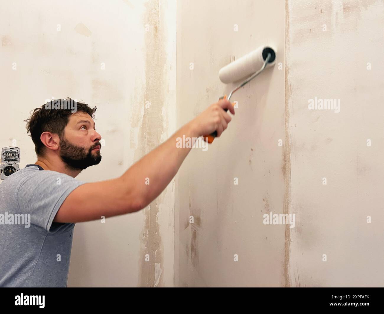 home improvement. Caucaisan man applying wall treatment, putting up ...