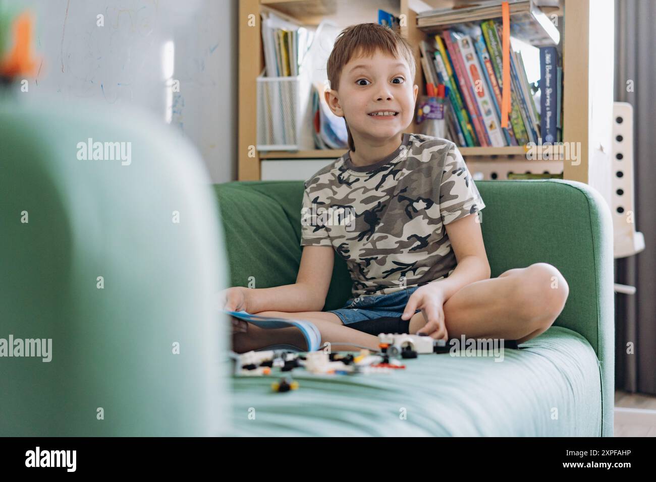 Little caucasian boy constructing a car with plastick blocks looking ...