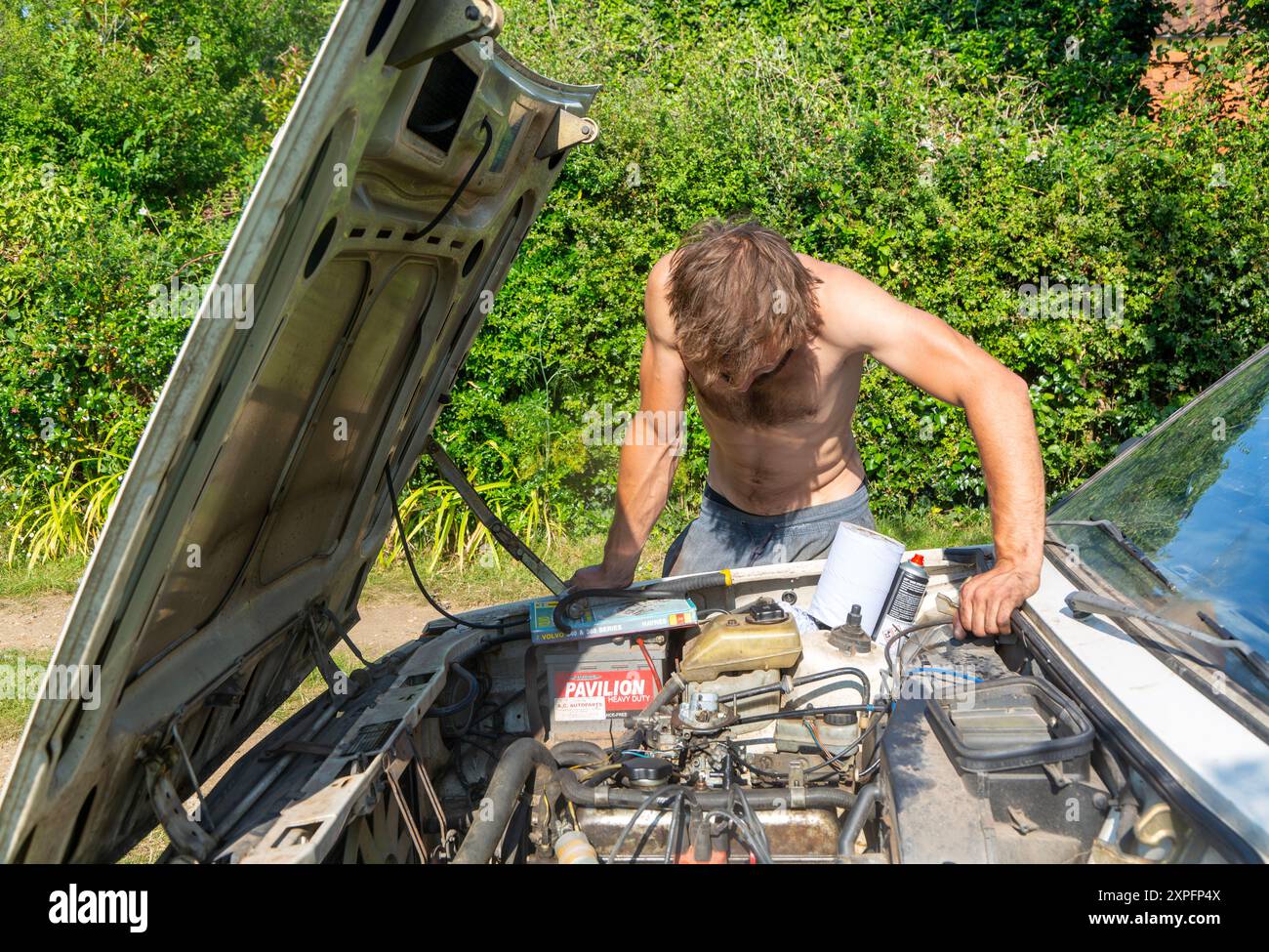 Young man portrait bare chest shirtless with beard car bonnet open ...