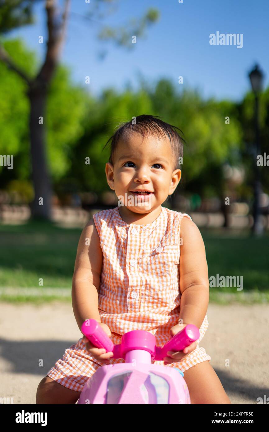 Portrait of a 1 year old Latina baby girl smiling playing outdoors with ...