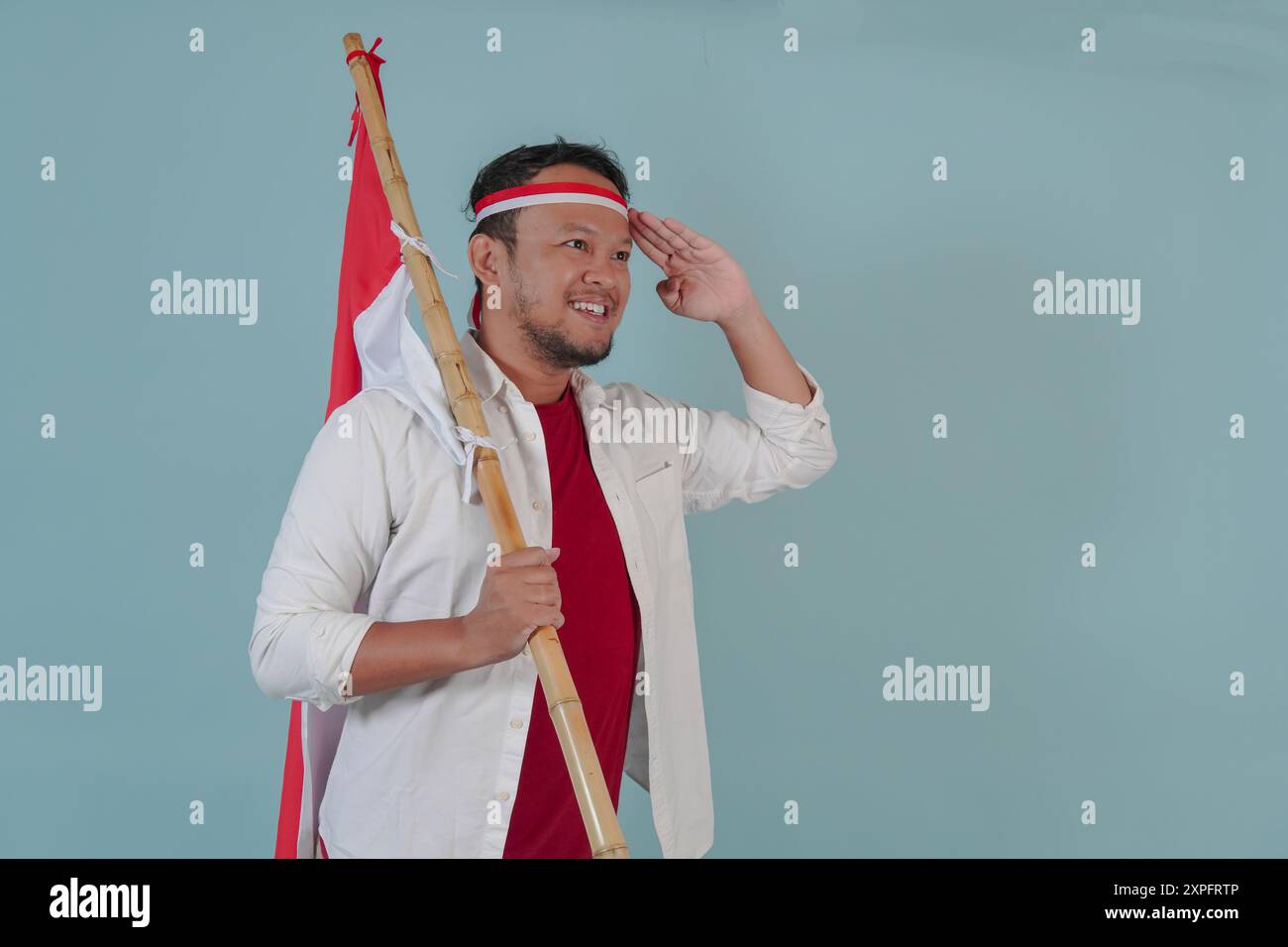 Happy Indonesian man is holding country flag while doing salute gesture ...
