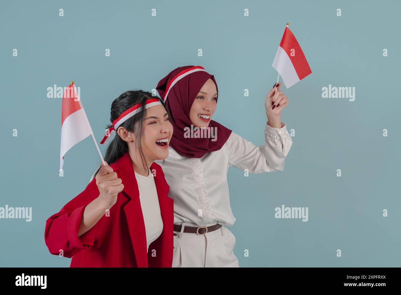 Two excited Indonesian women holding mini country flag smiling and ...