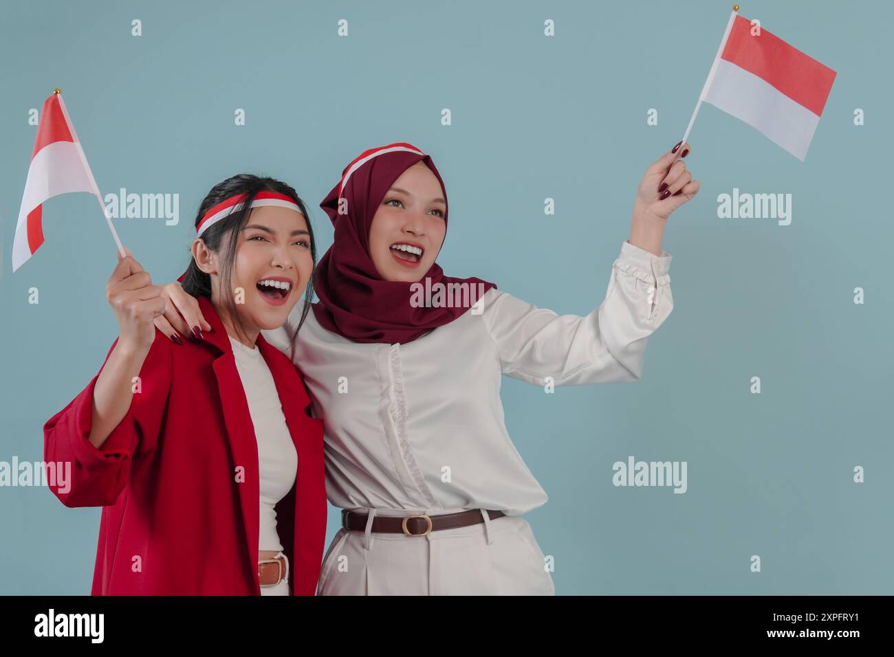 Two excited Indonesian women holding mini country flag smiling and ...