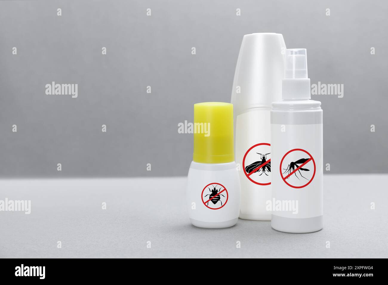 Different insect repellents in spray bottles on grey background, space ...
