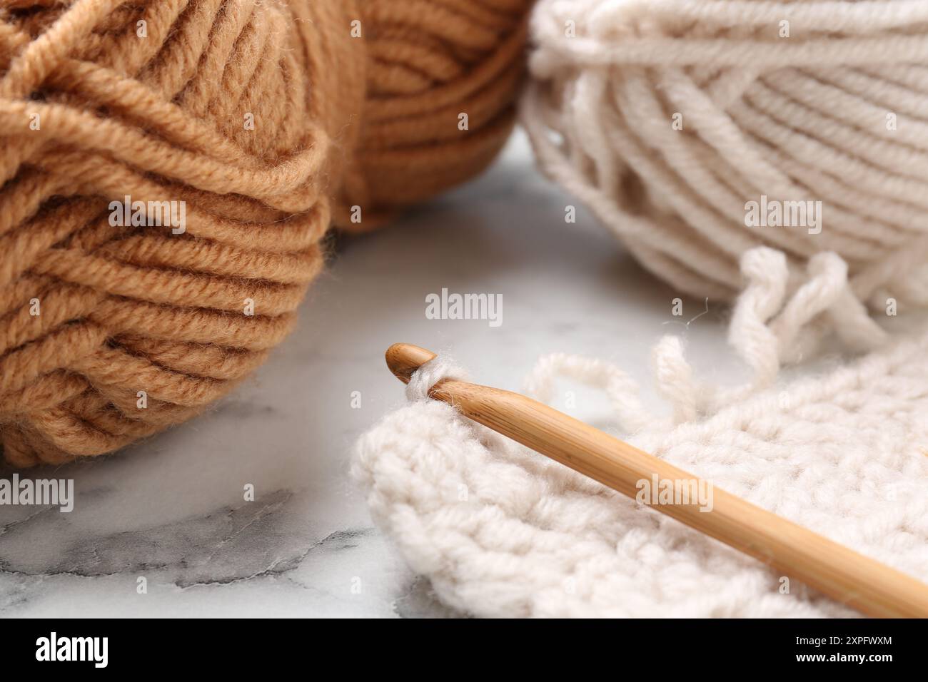 Crochet hook, pattern samples and colorful yarns on white marble table ...