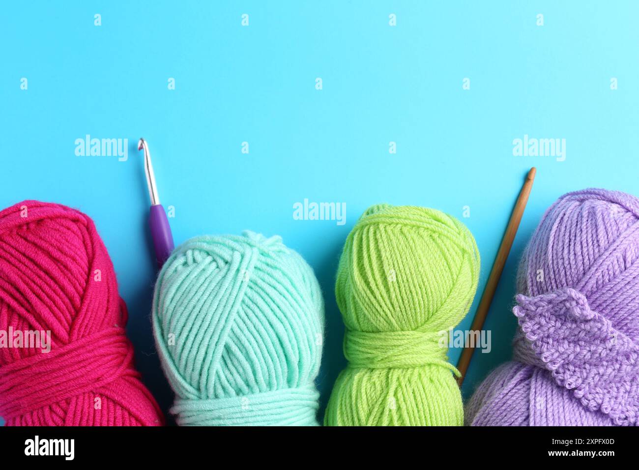 Colorful yarns, hooks and pattern sample on light blue background, flat ...
