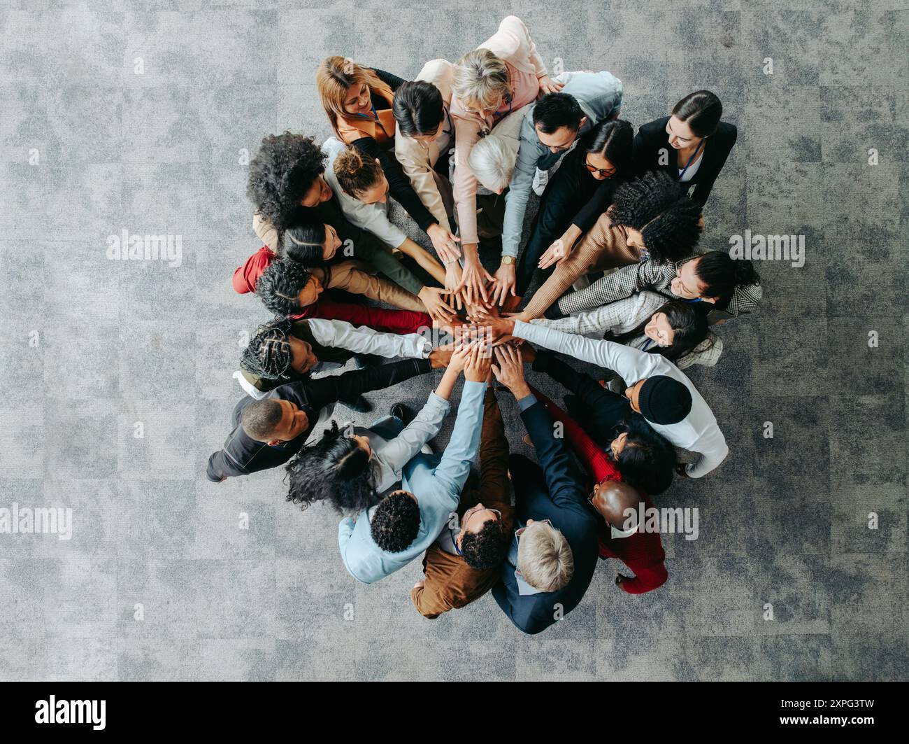 Top view of diverse professionals united in a hands-in huddle, symbolizing teamwork ...