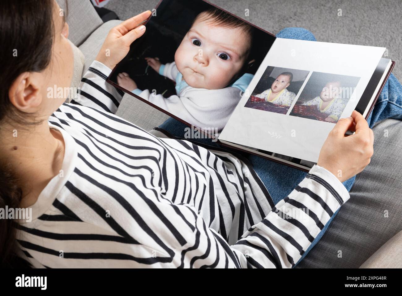 Woman looking at family photo album with her family and a baby Stock ...