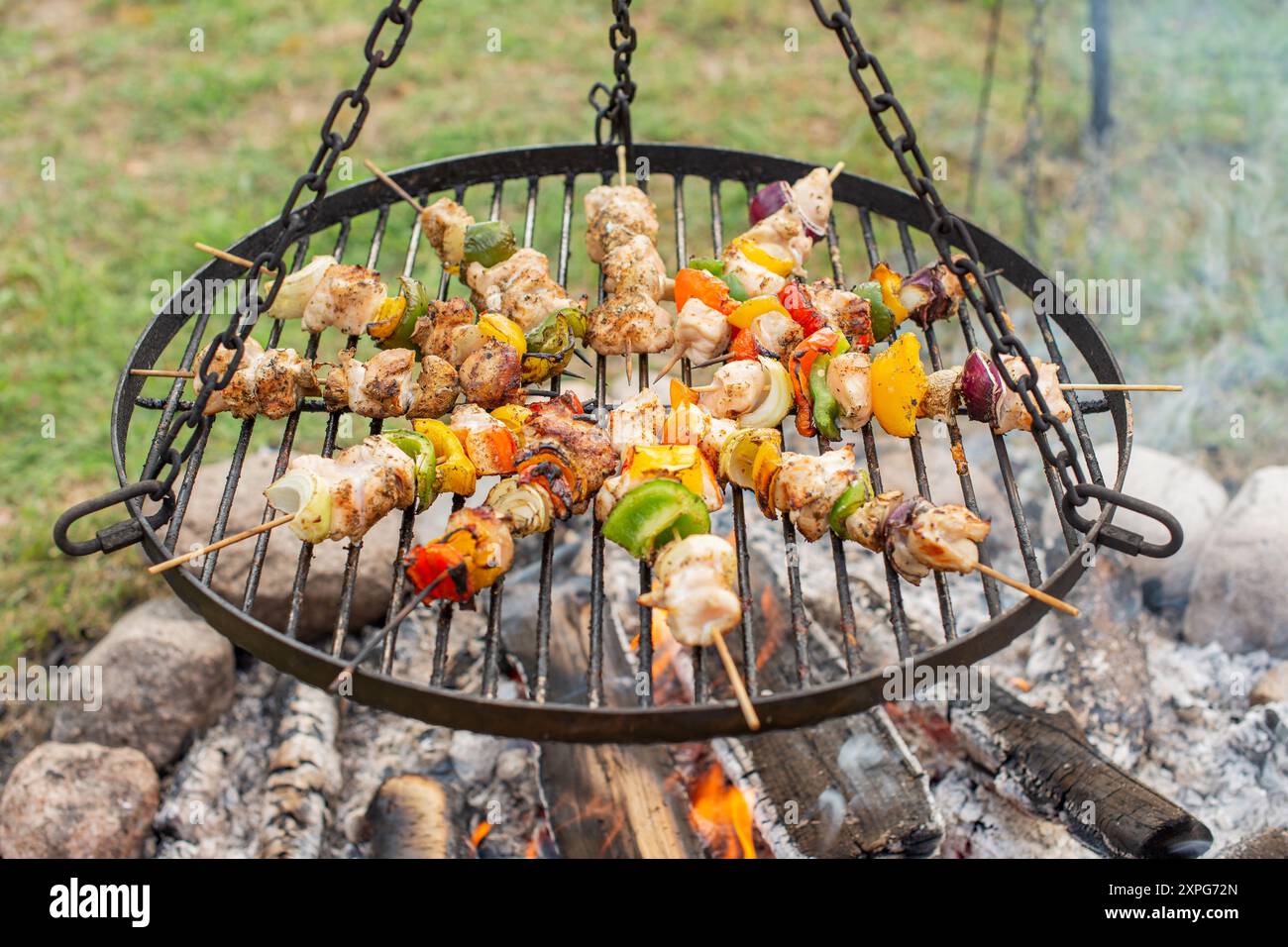 Chicken shashliks on a grill grate hanging on a chain Stock Photo - Alamy