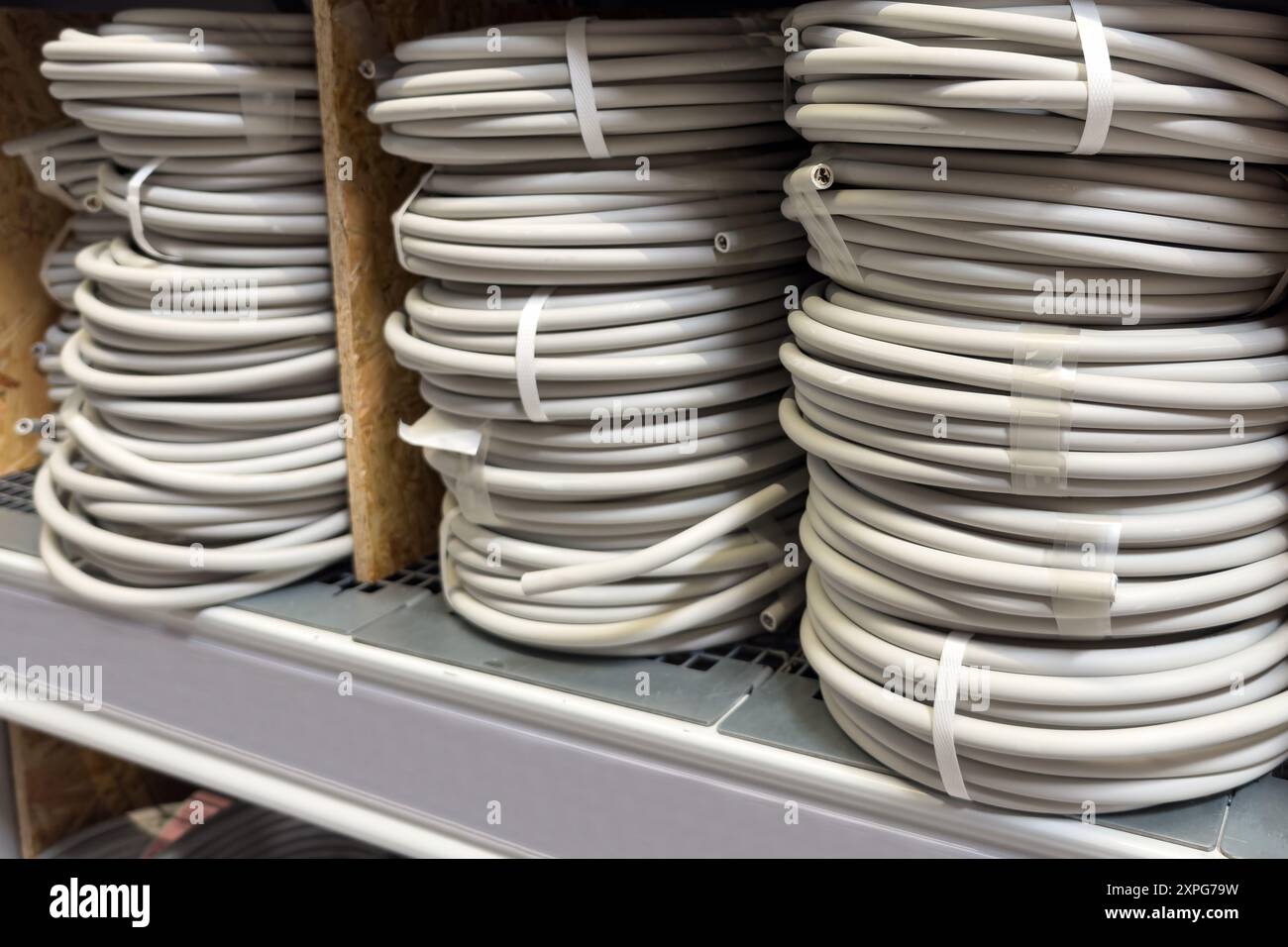 Coiled white electrical wires are organized on metal shelves in a ...
