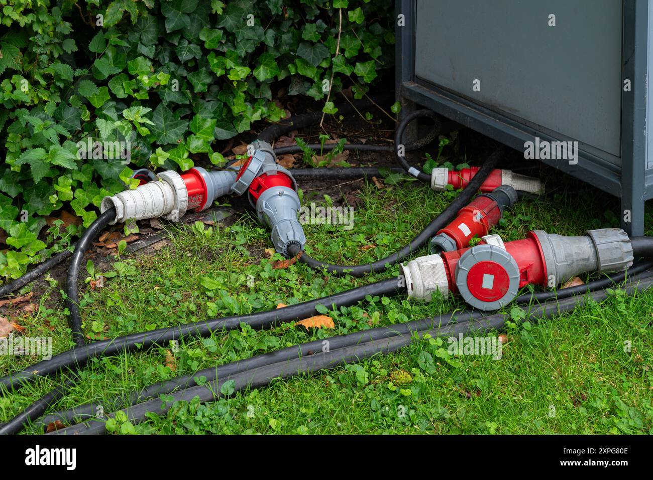 Heavy-duty electrical connectors and cables lie on the grass near a ...