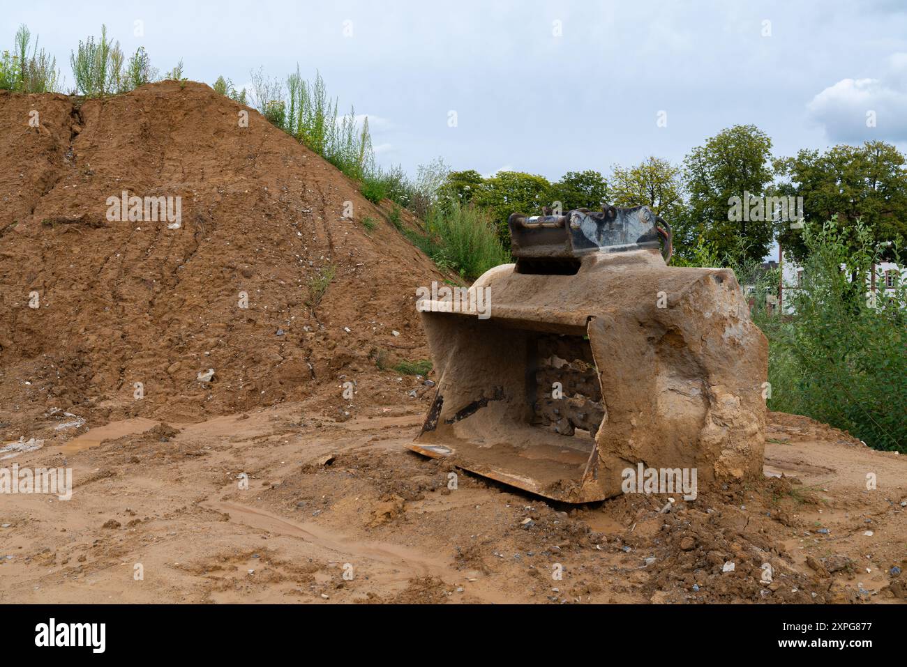 A large excavator bucket rests on a stone structure at an excavation ...