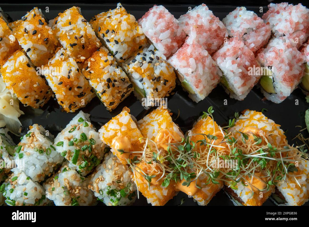 Delicious sushi rolls side by side in a black tray. Top view on black ...
