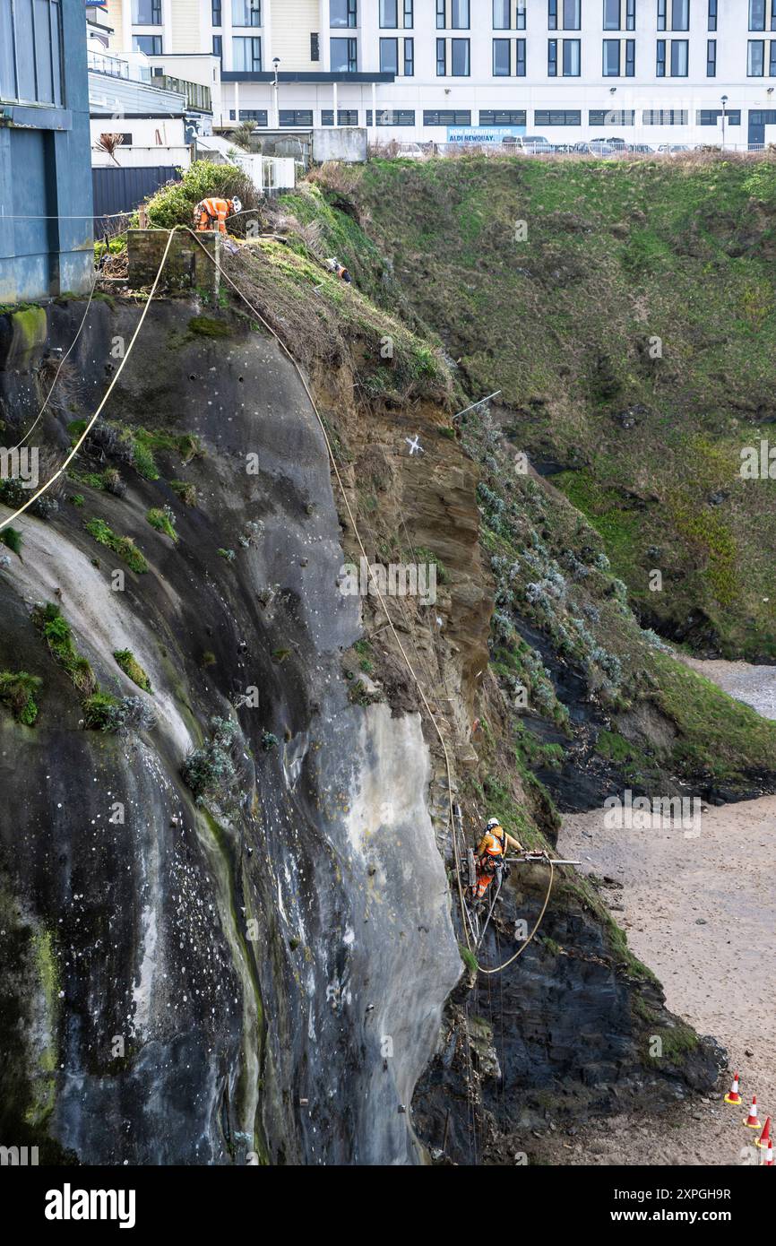 A worker suspended by ropes working to stabilise stabilize the cliff ...
