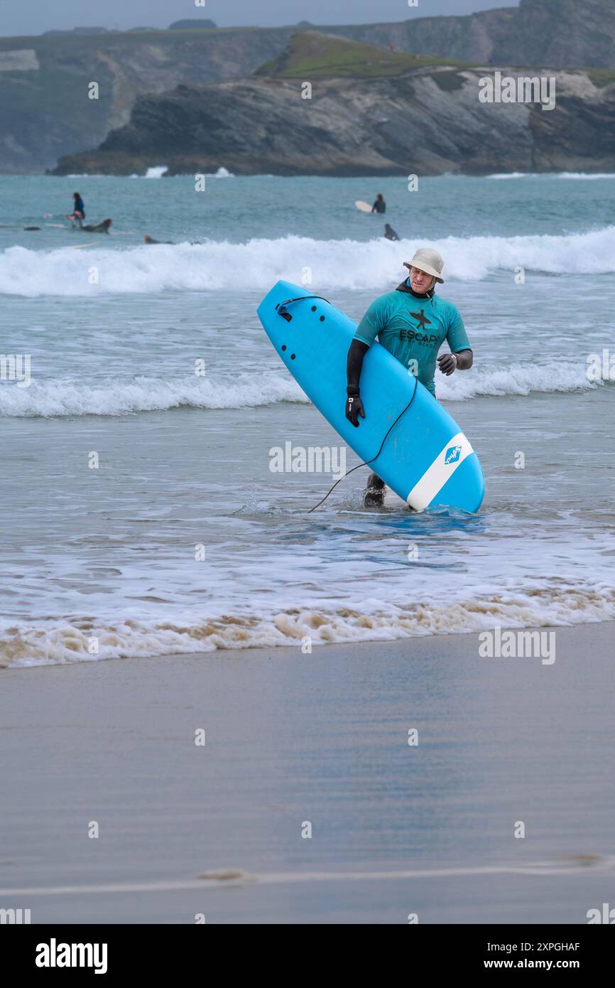 An Escape Surf School surfing instructor teacher walking out of the sea ...