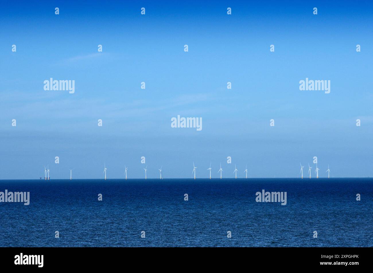 A row of wind turbines at sea on the horizon on an offshore wind farm ...