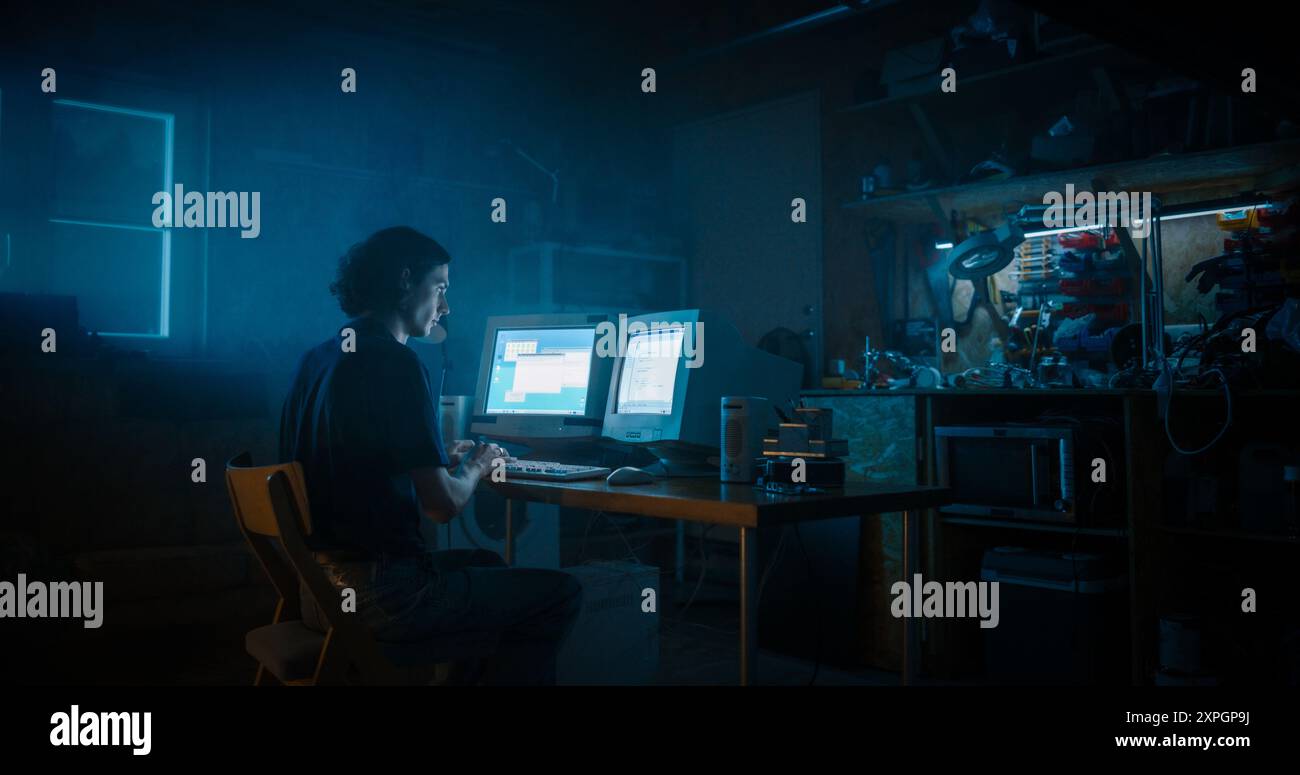 Caucasian Male Programmer Using Old Desktop Computer With Two Monitors In Retro Garage Late At
