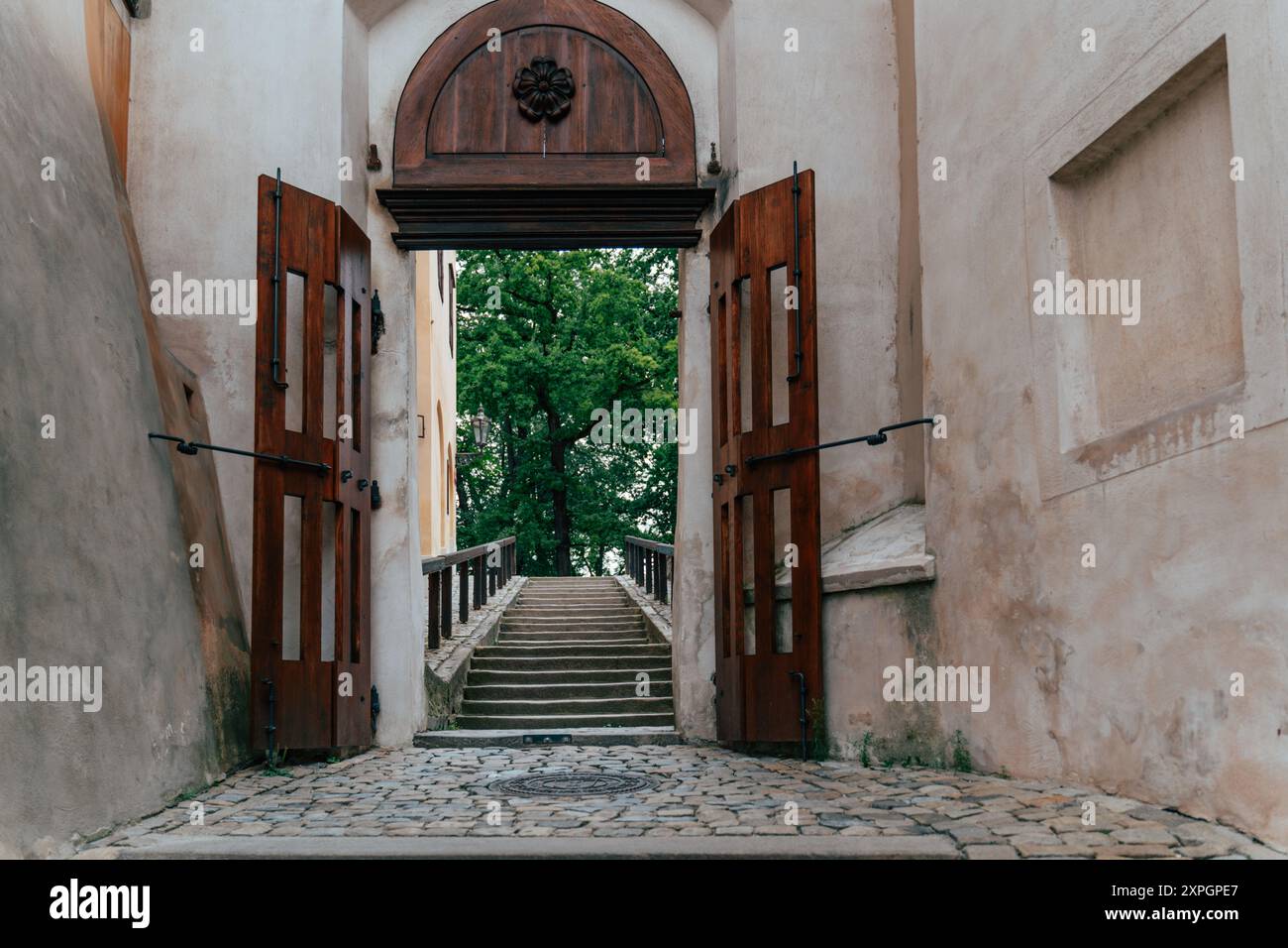 The grand wooden doors stand open, revealing a pathway of stone steps ...
