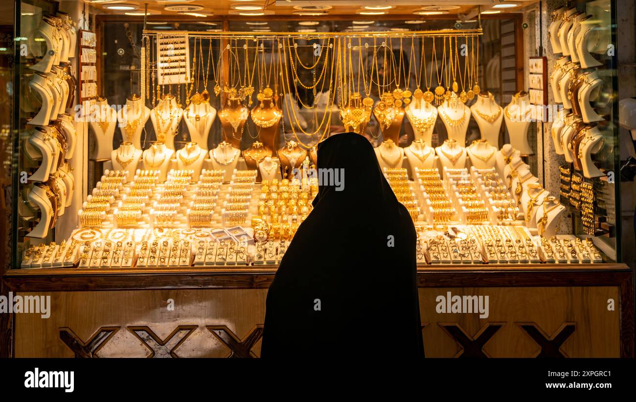 Iranian woman in hijab black dress looking at the display at a gold ...