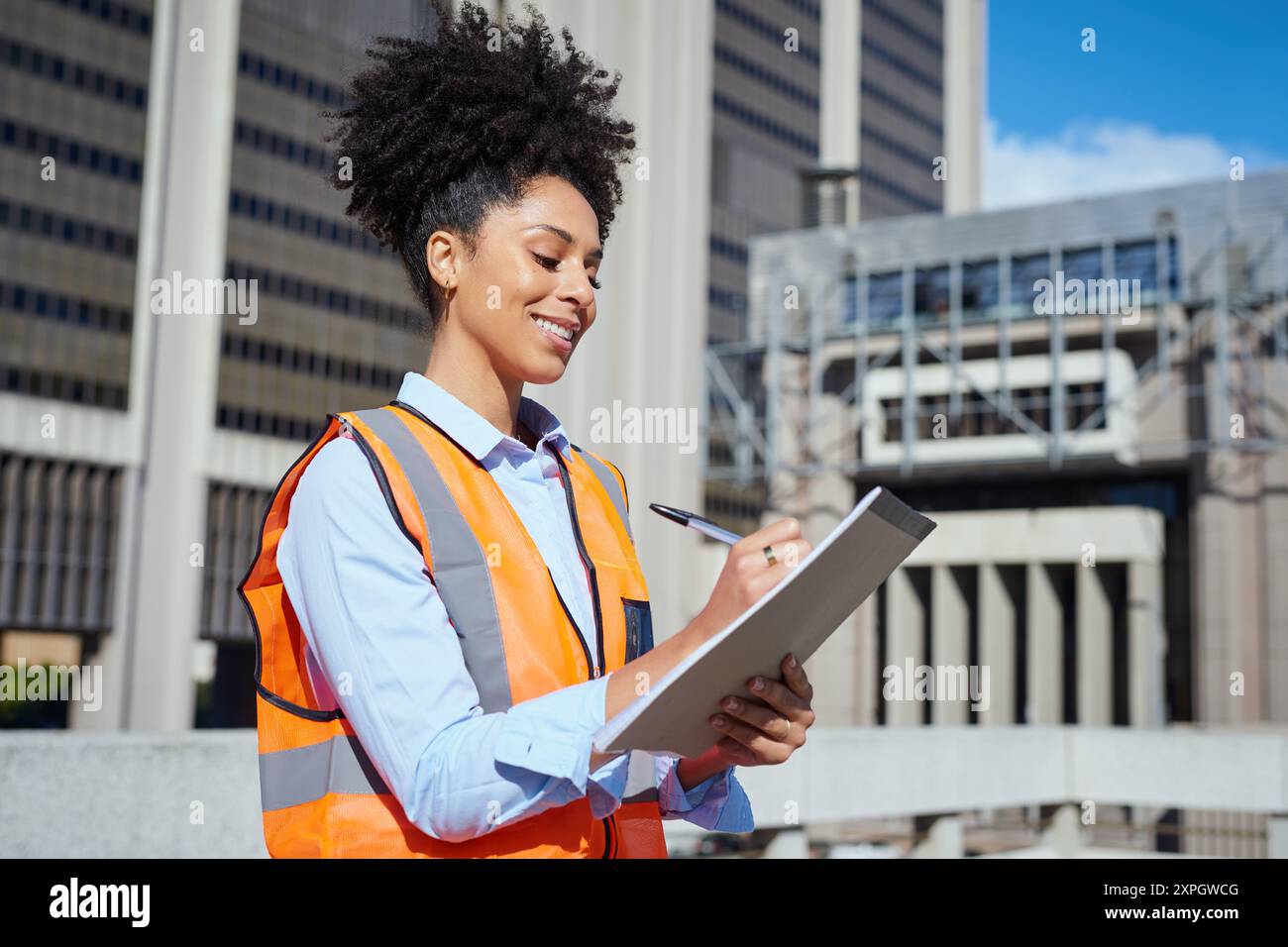 Female Construction Worker in Safety Vest Smiling and Taking Notes ...