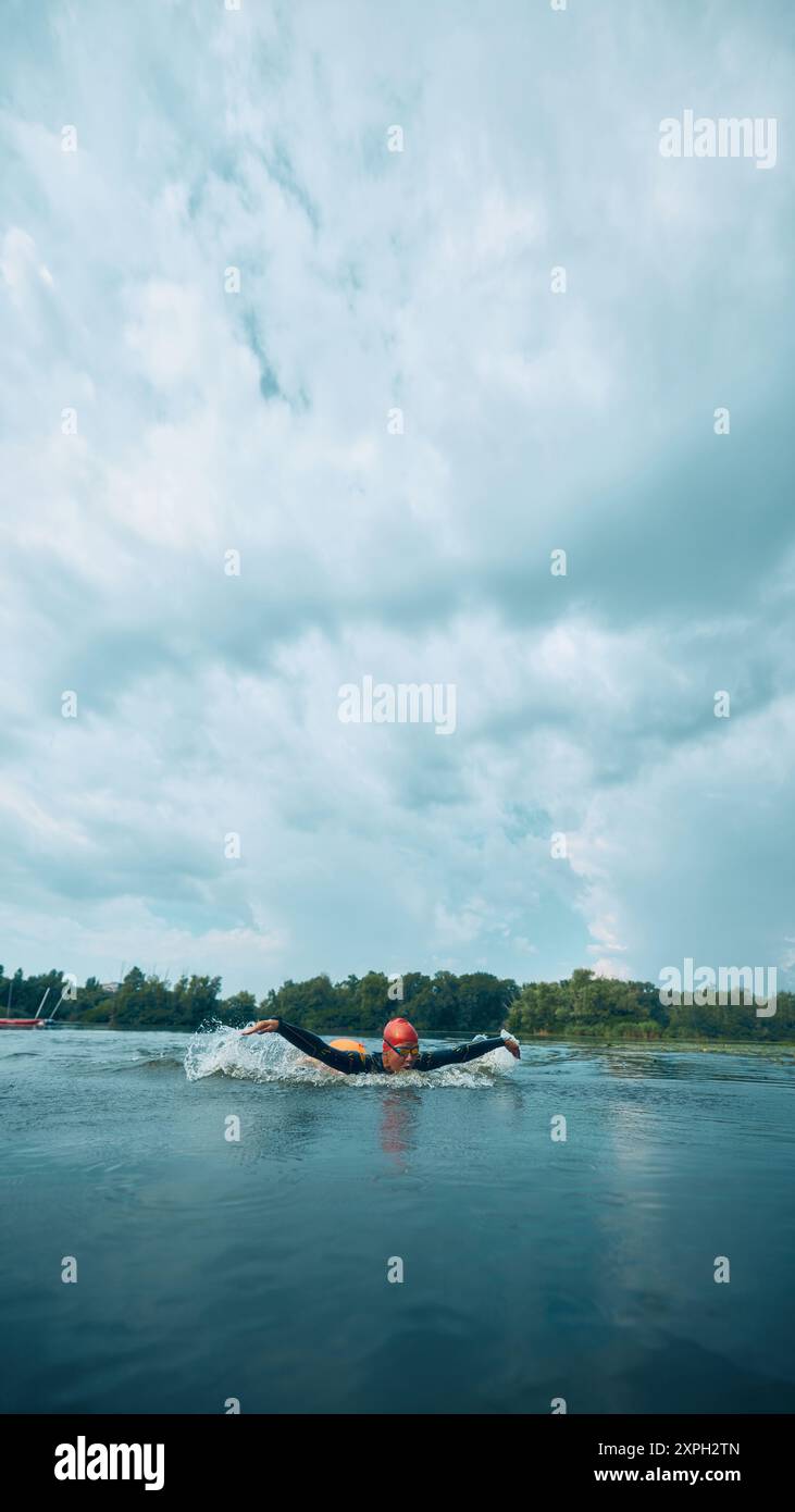Athlete in black wetsuit and red cap enthusiastically swimming through ...