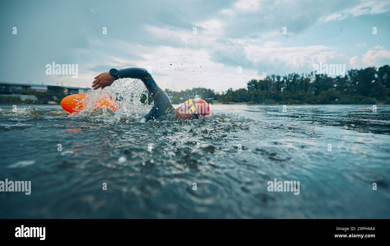 Gliding through river water, female athlete in black wetsuit and red ...