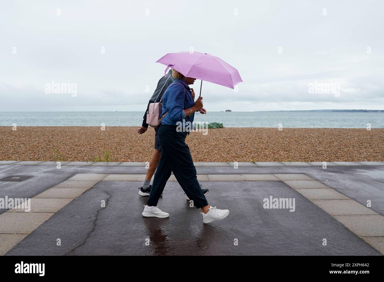 People shelter from the rain under umbrellas as walk along Southsea ...