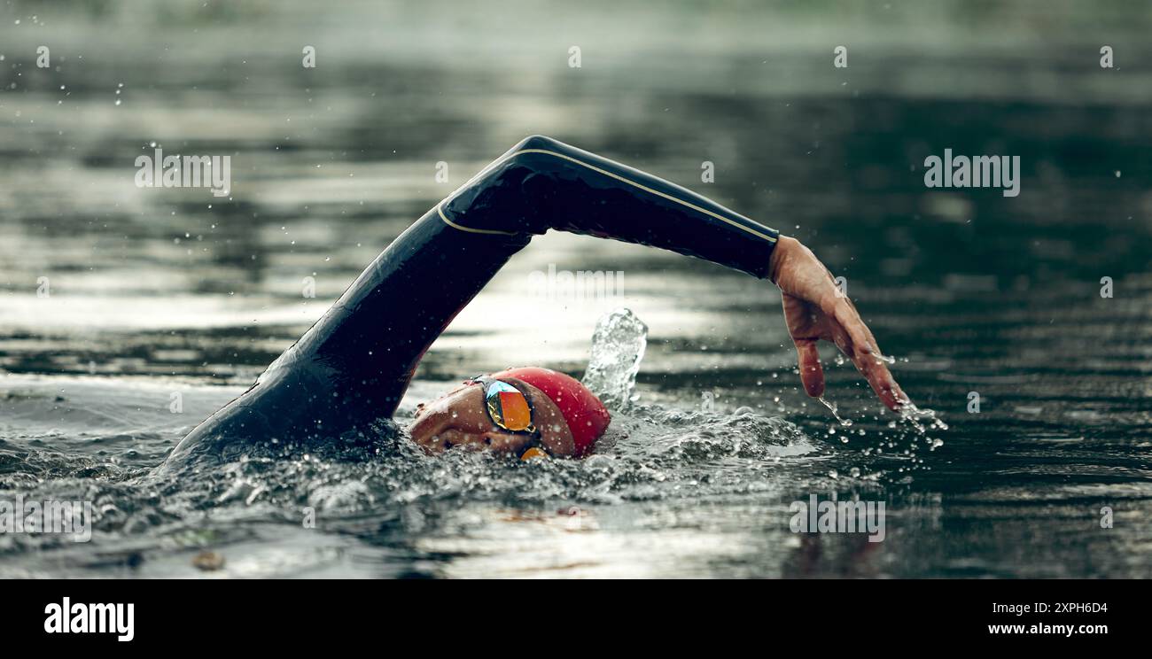 Triathlete in red swim cap and black wetsuit practices freestyle stroke ...